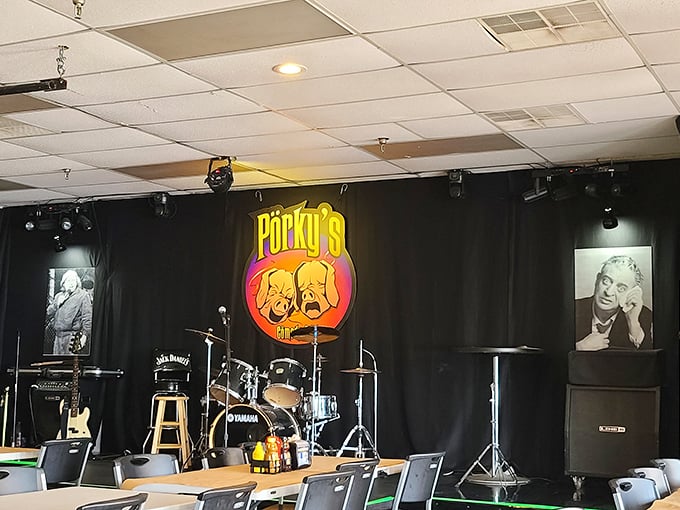 The stage awaits its performers, complete with comedy-tragedy masks logo. By night, this space hosts laughs as satisfying as the smoked meats.