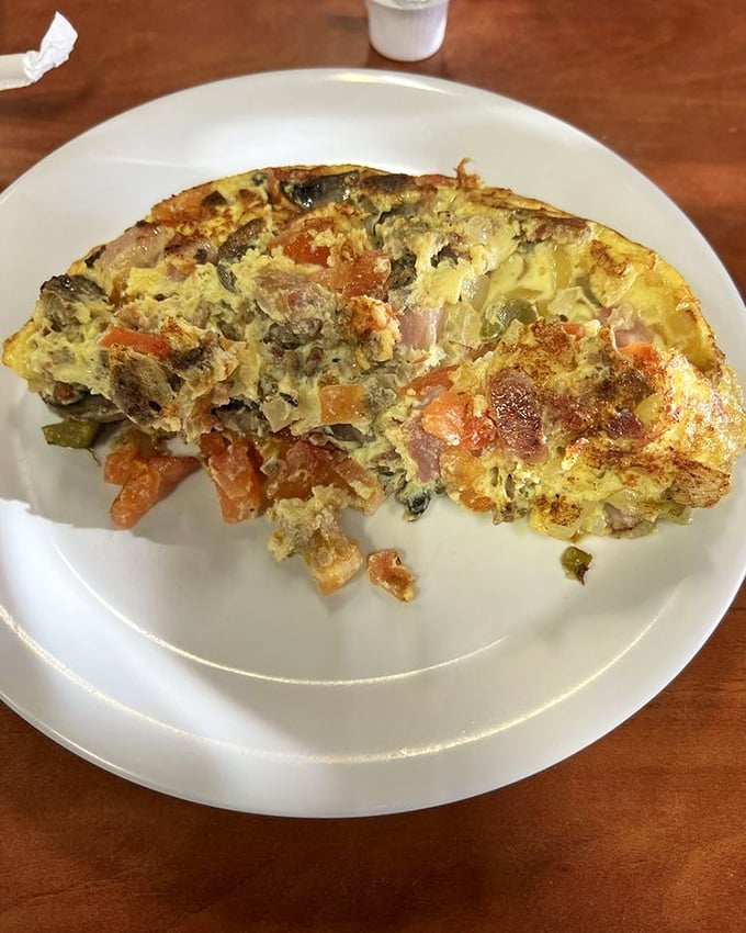 This hearty omelet, packed with vegetables and ham, represents breakfast democracy – where ingredients from all food groups come together in eggy harmony.