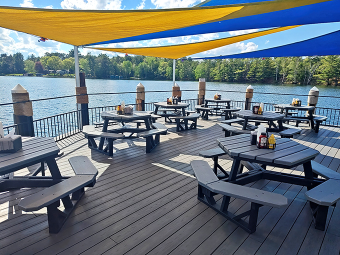 Outdoor dining under blue and yellow canopies creates the perfect lakeside escape – where picnic tables and water views elevate every bite to vacation status.