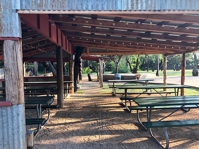 Outdoor dining under corrugated metal roofing—where the Texas breeze carries conversations and the scent of mesquite-grilled perfection.