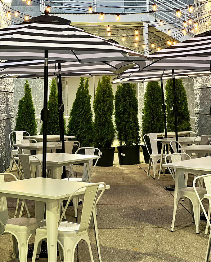 The outdoor patio—where striped umbrellas and potted greenery create an urban oasis perfect for people-watching while savoring every last crumb.