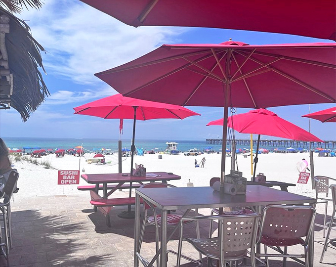 Pink umbrellas frame a view that belongs on your screensaver—powdery white sand meeting emerald waters while you contemplate another round.