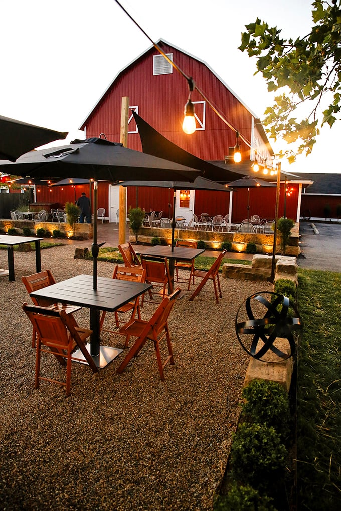 Outdoor seating under string lights where summer evenings stretch as long as the conversations. The barn glows amber against the twilight sky.