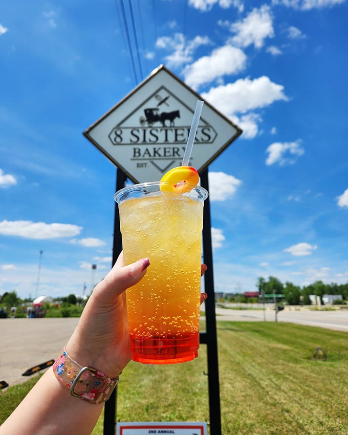 A sunshine-colored beverage against the bakery sign—proof that 8 Sisters knows refreshment doesn't stop at solid food.