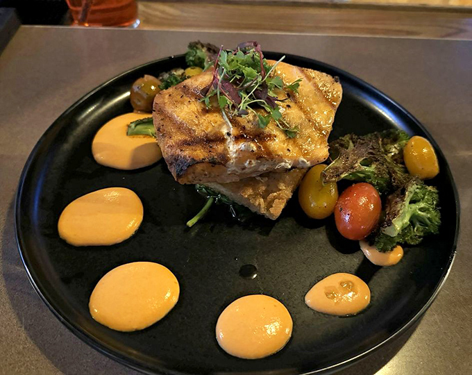 Salmon that's been introduced to fire and decided they make a beautiful couple, surrounded by artistic sauce flourishes.