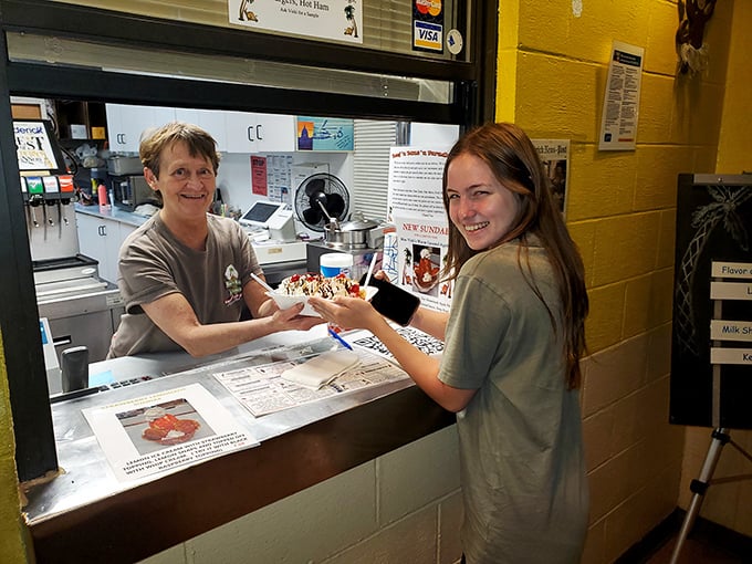 The image shows staff members at the counter, sharing a genuine smile while serving up happiness on a plate.