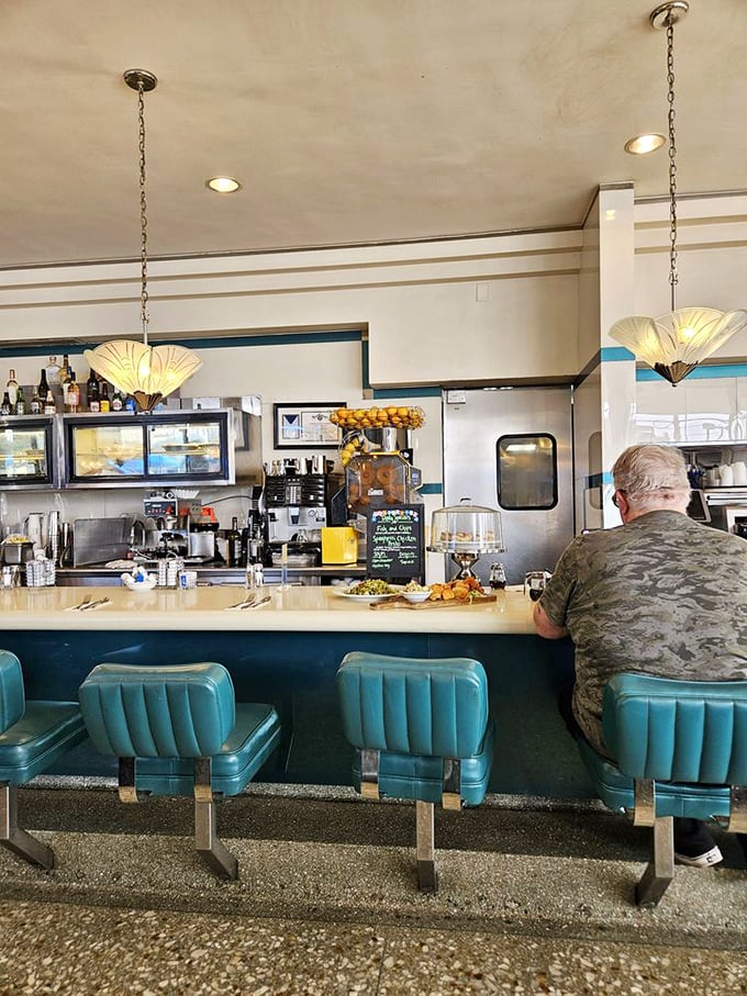The counter where regulars have been telling stories for decades. Those fan-shaped pendant lights are pure mid-century magic.