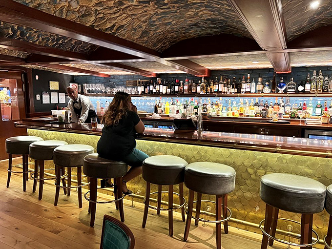 The bar's scale-like backdrop shimmers like fish passing through deep waters—a perfect visual metaphor for the liquid treasures waiting to be discovered in each glass.