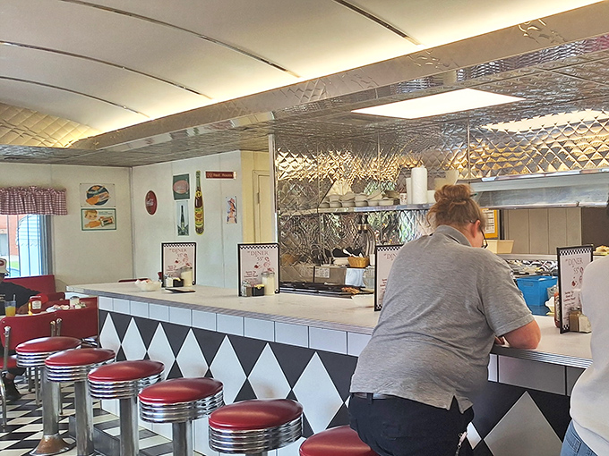 The counter – where solo diners find community, watching short-order ballet performed behind a diamond-patterned stage of black and white.