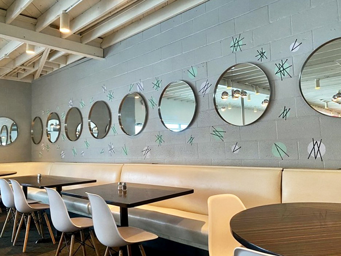 A row of circular mirrors creates a space-age vibe against cool gray walls, reflecting the thoughtful design that makes dining here a pleasure.