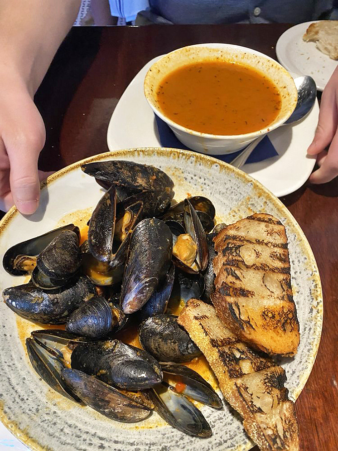 These mussels aren't just shellfish—they're little black submarines delivering payloads of briny-sweet flavor, ready to be sopped up with that perfect grilled bread.