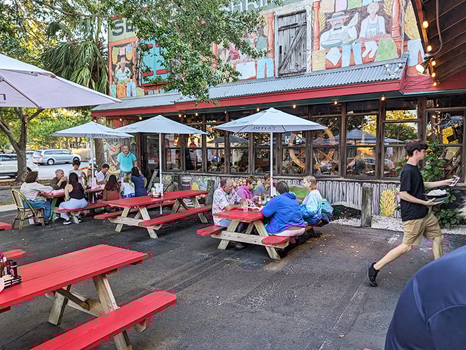 Red picnic tables under umbrellas offer al fresco dining with a side of people-watching. Florida's unofficial state sport: eating seafood outdoors while others shovel snow up north.