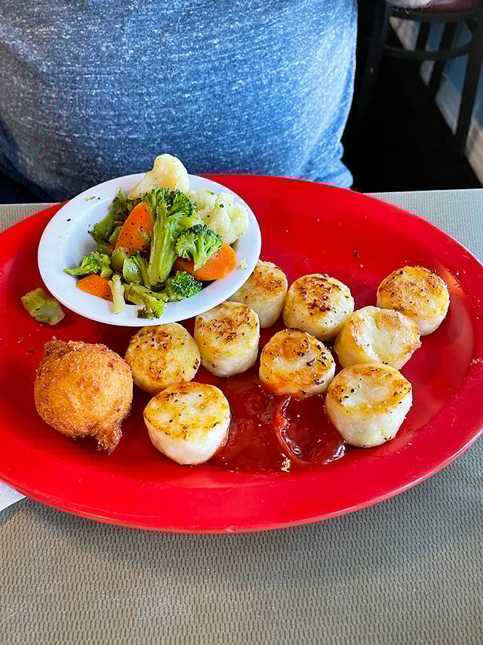 Perfectly seared scallops with a side of vibrant vegetables prove that simple preparation lets quality ingredients shine. That single hush puppy is the chef's exclamation point. 