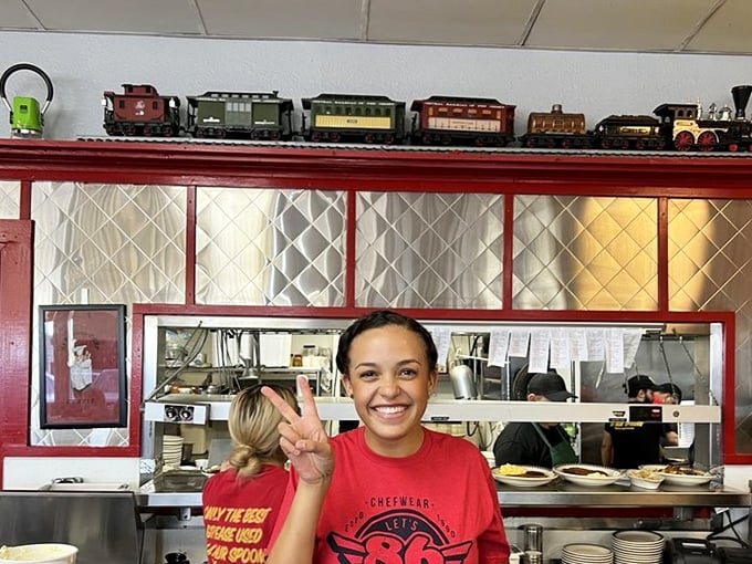That smile says, "Yes, our grits really are that good." The peace sign is just bonus hospitality—Southern charm in visual form.
