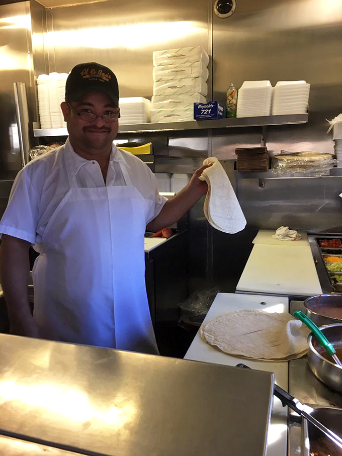 The maestro at work, fresh tortilla in hand. That smile says he knows exactly what magic he's about to create.