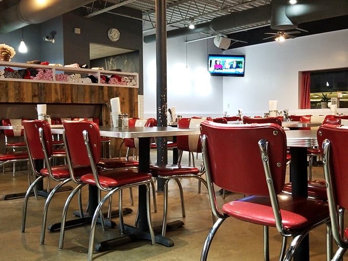 Red chairs pop against industrial-chic surroundings in a dining room where strangers become temporary breakfast companions, united by their quest for the perfect morning meal.