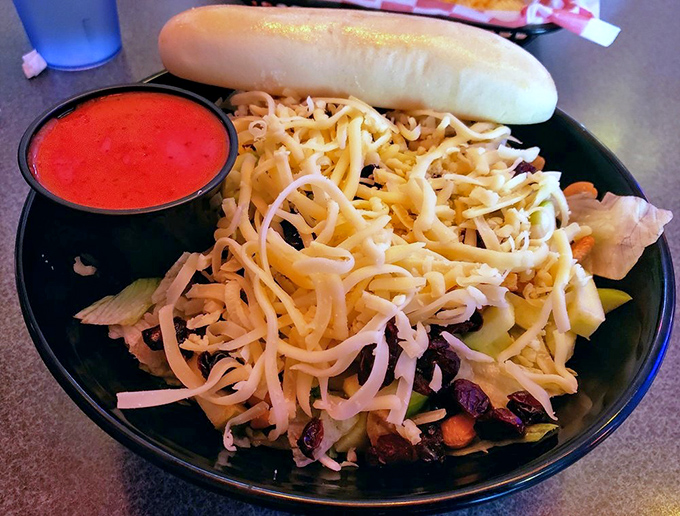This salad doesn't just have toppings—it has architecture. A breadstick bridge spans a colorful landscape of vegetables, cheese, and what appears to be the kitchen sink, all in perfect harmony. 