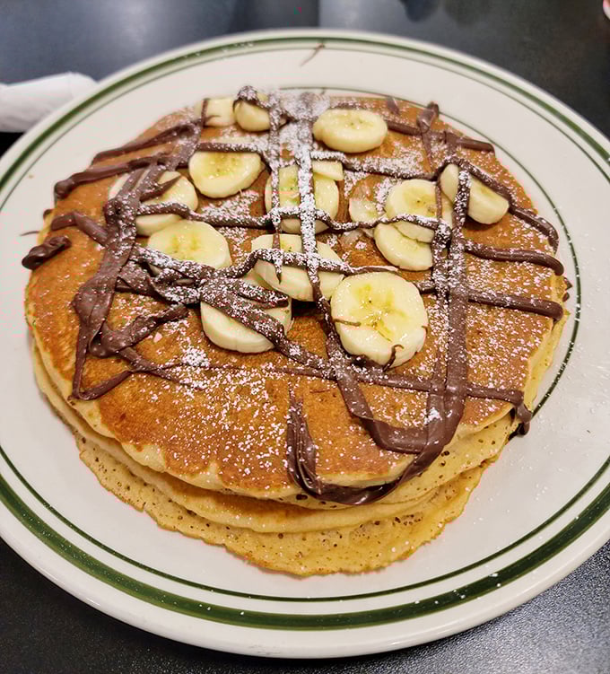 Pancakes stacked high, drizzled with chocolate, and topped with bananas – breakfast that doesn't pretend to be anything but delicious indulgence.
