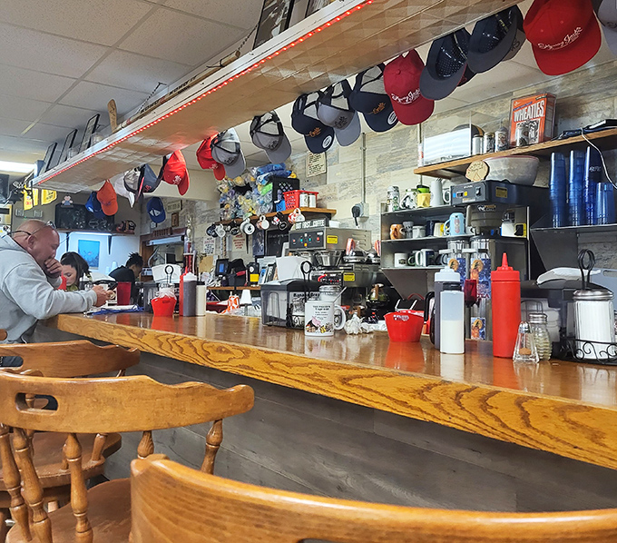 The counter where breakfast dreams come true—complete with a parade of baseball caps that have witnessed countless "first coffee" moments.
