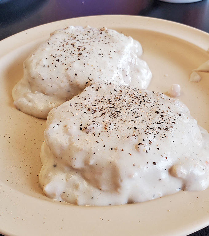 Biscuits and gravy so good they could broker peace treaties – fluffy pillows drowning in creamy, peppery perfection.