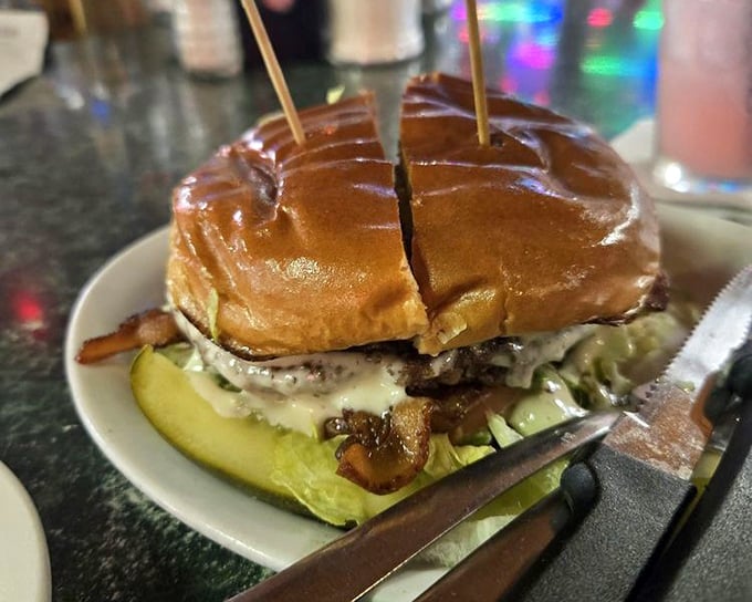 This burger isn't just served – it's presented with a toothpick flag planted like a delicious conquest, pickle and all.