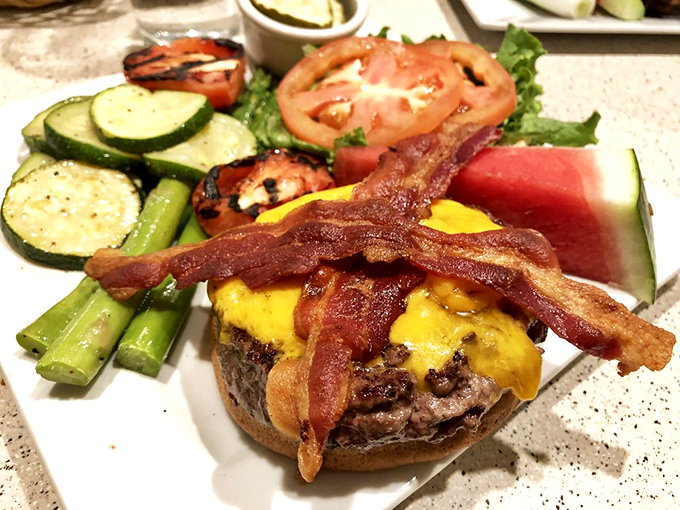The burger that bridges breakfast and lunch—topped with melted cheddar and bacon strips that salute you with their crispness.