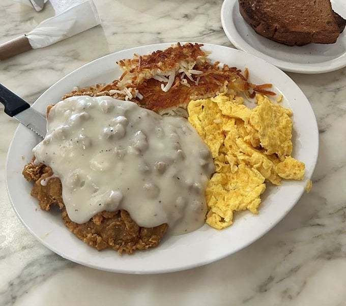 Chicken fried steak with gravy represents America's greatest contribution to breakfast—a dish that laughs in the face of moderation and whispers, "Live a little."