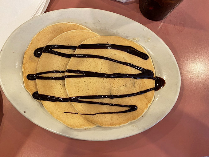 Pancakes dressed in their Sunday best – chocolate drizzle creating the kind of breakfast masterpiece that makes you pause before diving in.