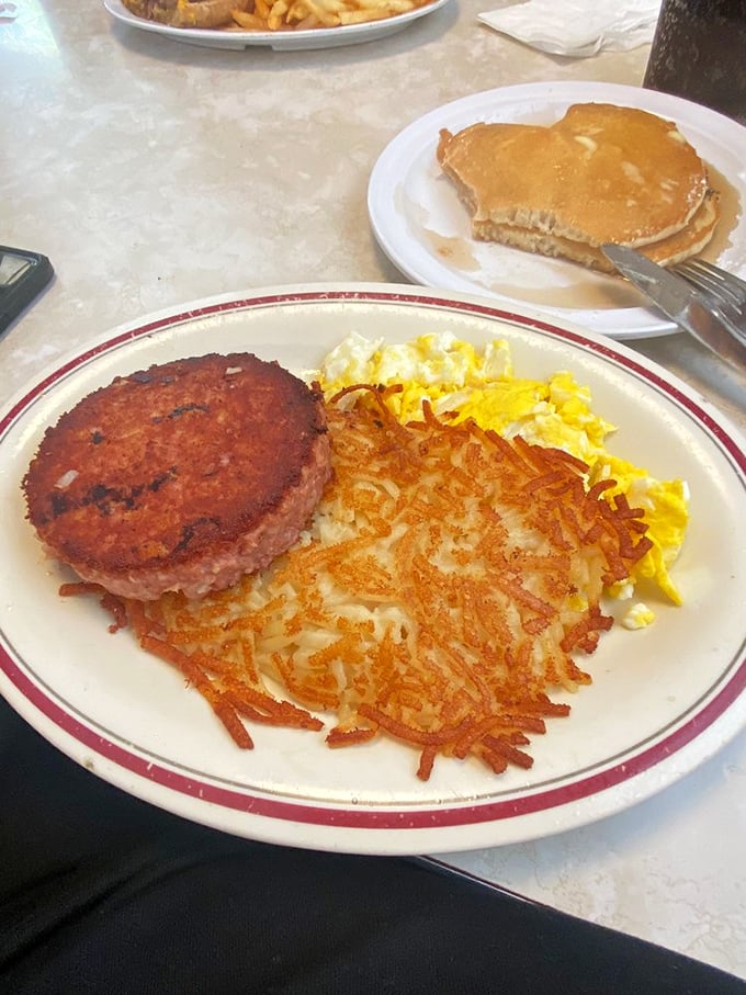 The breakfast of champions who don't care about cholesterol—crispy hash browns, scrambled eggs, and a ham steak that means business.