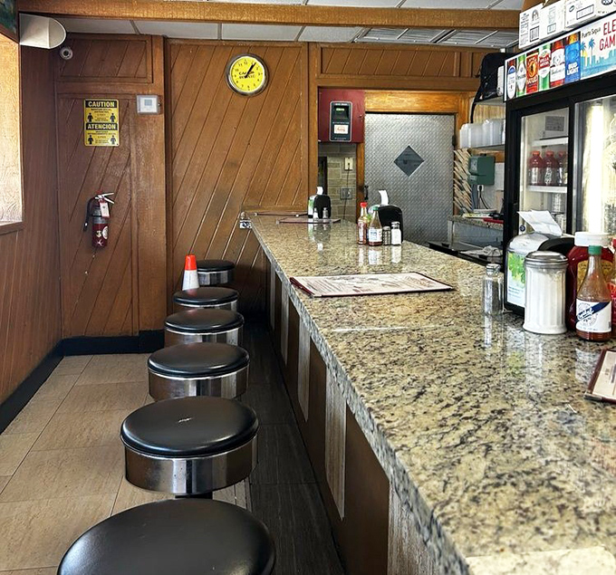 Classic diner counter seating where regulars have worn their loyalty into the very stools, each one a front-row seat to culinary theater.