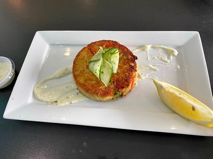 This crab cake doesn't hide behind fillers—it stands proudly alone, a golden-crusted island of crab in a sea of delicate sauce.