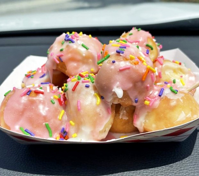 Donut holes in pink glaze with sprinkles—bite-sized joy bombs that somehow taste better than their full-sized counterparts, defying all laws of physics.
