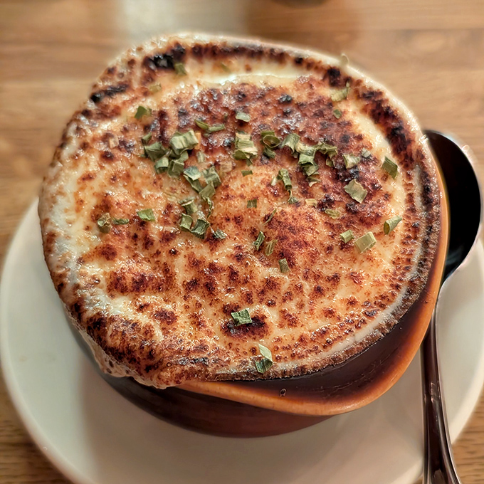 This isn't just French onion soup—it's a geological wonder with a molten cheese cap that stretches dramatically with each spoonful.