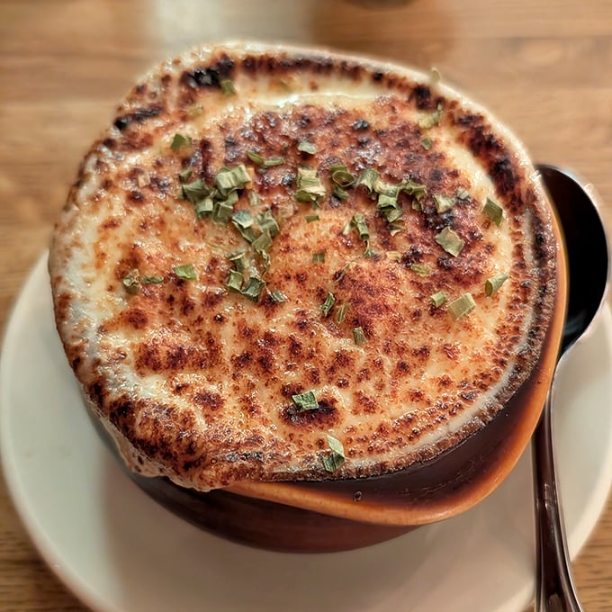 This isn't just French onion soup—it's a bubbling cauldron of comfort topped with a golden cheese canopy that stretches dramatically with each spoonful.