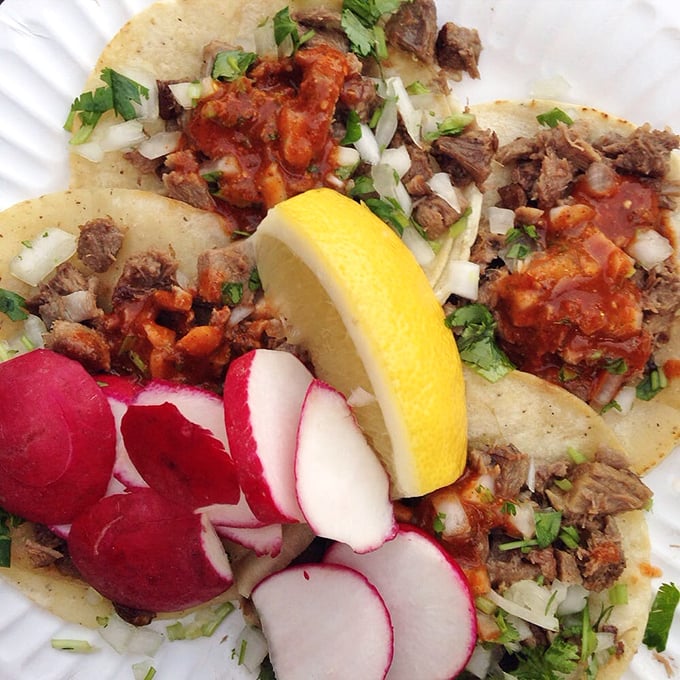 Lengua tacos garnished with radish medallions and a lemon crown – a dish that transforms the hesitant into true believers with just one bite.