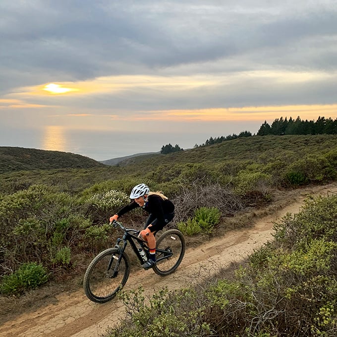 Mountain biking with an ocean sunset backdrop – because some exercise routines deserve better scenery than a gym's motivational poster.