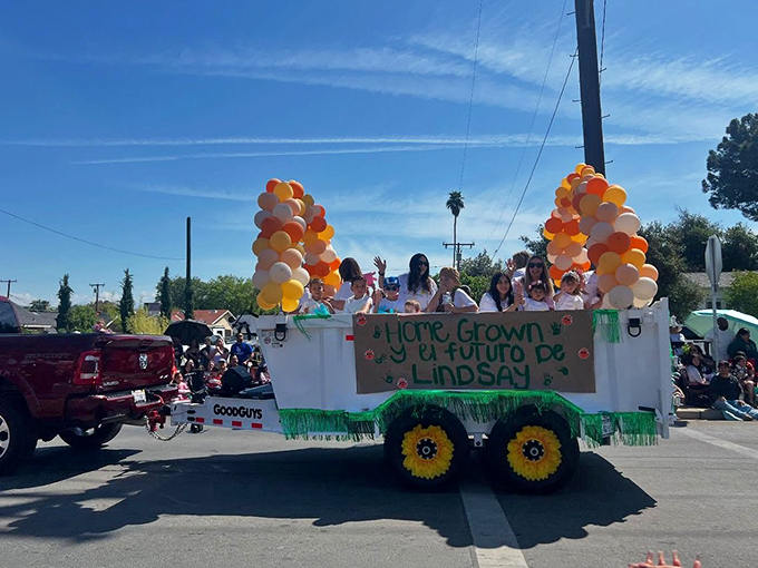 "Home Grown y el futuro de Lindsay"—parade floats celebrate the town's agricultural heritage and its bright, balloon-decorated future.