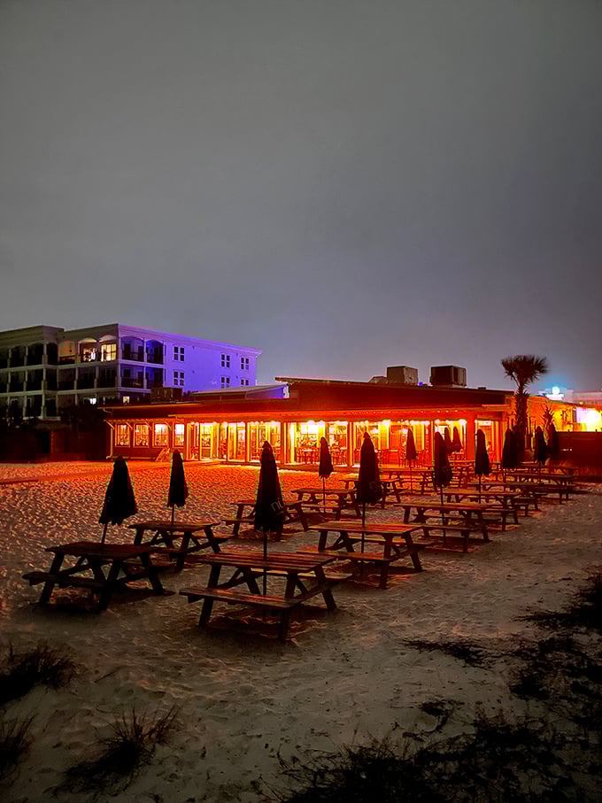 Nighttime transforms Surf Hut into a glowing beacon of beachfront dining. Those picnic tables have stories that would make a romance novelist blush.