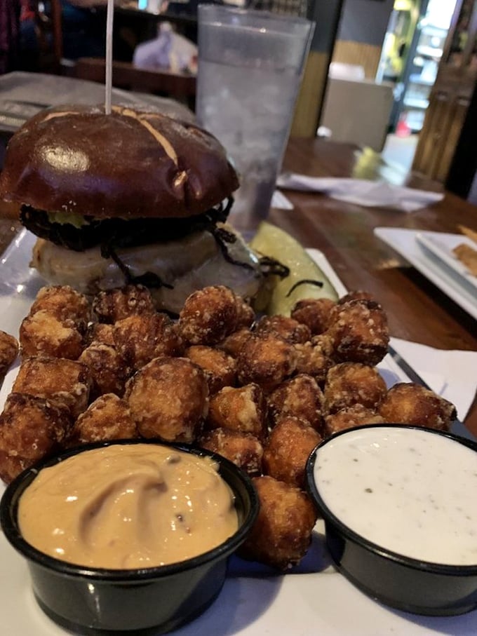 This burger with sweet potato tots isn't just lunch—it's an edible art installation with dipping sauces as the perfect supporting cast.