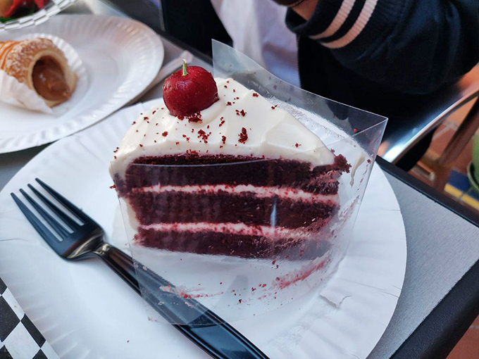 This red velvet cake slice isn't playing around—it's three layers of crimson intensity that makes grocery store versions hang their heads in shame.