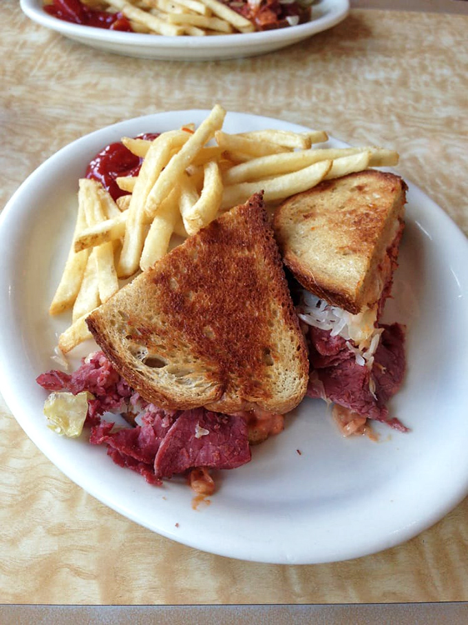 The Reuben sandwich—where corned beef and sauerkraut hold their union ceremony beneath a melted Swiss canopy with crispy fries as witnesses.