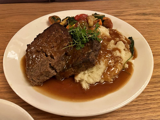 Meatloaf reinvented as the hero it deserves to be—tender, savory, and draped over creamy mashed potatoes with seasonal vegetables playing supporting roles.