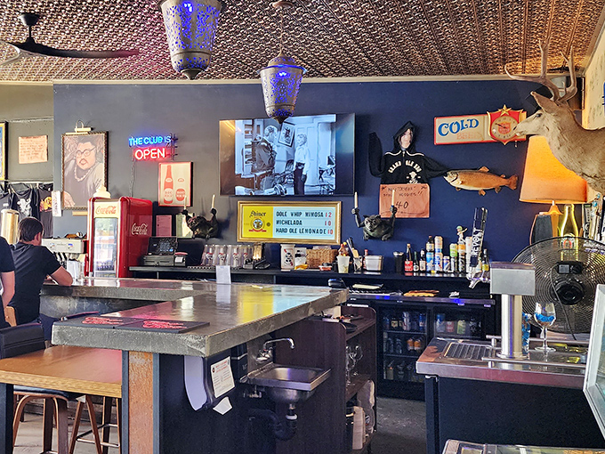 The bar area—where taxidermy meets neon in a uniquely American celebration of cold drinks and hot BBQ.