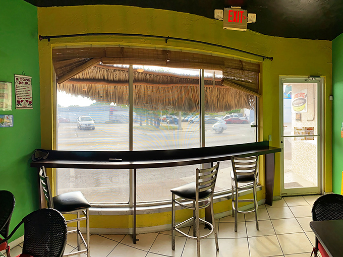 The thatched window treatment isn't just decor—it's a frame for daydreaming about beaches while you wait for food that will transport you there anyway.