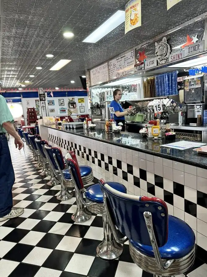 The counter where regulars have worn their own invisible nameplates into the seats, a front-row view to short-order magic.