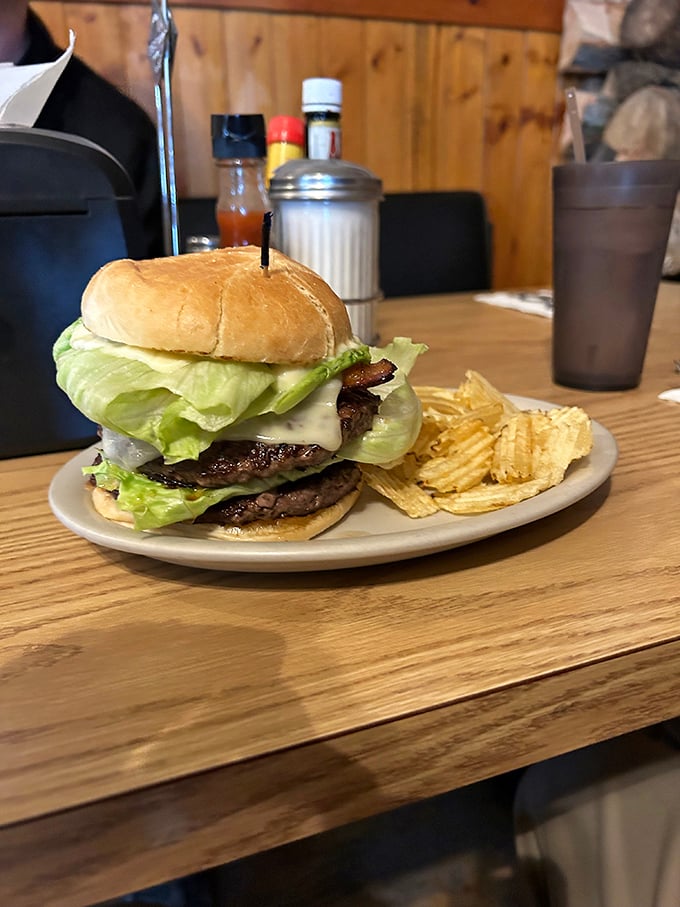 A burger that requires a game plan before the first bite, stacked tall enough to make you wonder if your jaw will unhinge like a snake's.