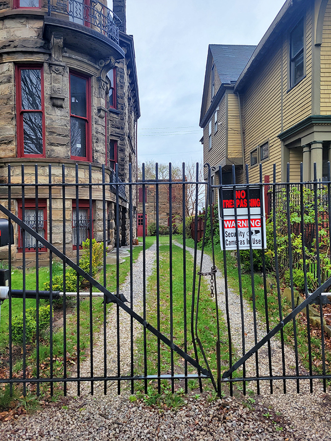 The wrought iron gate stands sentinel, its "No Trespassing" sign a modern addition to centuries-old boundaries between the ordinary world and whatever waits beyond.