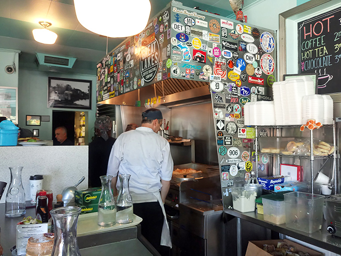 Where the magic happens—a kitchen wall plastered with stickers telling stories of travels, while cooks craft morning masterpieces.