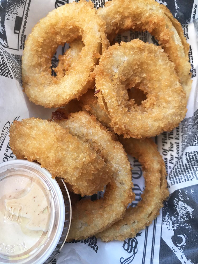 These onion rings aren't just fried circles—they're golden halos of crispy perfection that make you believe in a benevolent culinary deity.