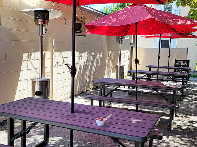 The outdoor seating area offers purple picnic tables under red umbrellas – a splash of color that matches the cafe's vibrant personality.